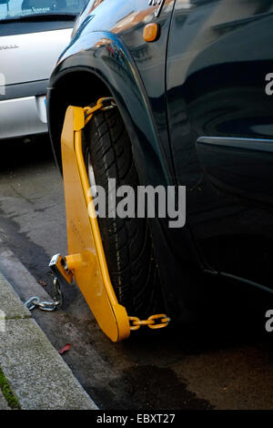 bright yellow wheel clamp on car parked in urban street Stock Photo - Alamy