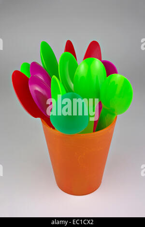 Plastic dishes bright colors for a picnic. Pink background and blue ...