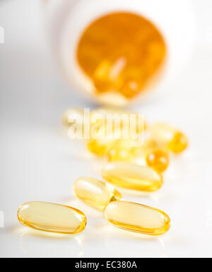 shiny yellow vitamin e fish oil capsule spilling out of pill bottle ...