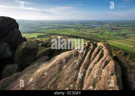 Weathered gritstone rocks on the summit of Hen Cloud with view across a ...