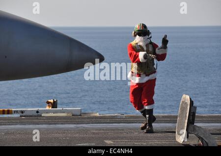 A US Navy sailor dressed as Santa Claus directs aircraft movement ...