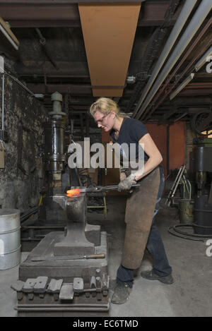 female blacksmith working at ambos with hammer on redhot steel Stock ...