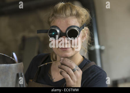 young female blacksmith with goggles, soldering metal Stock Photo - Alamy