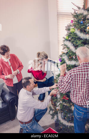 Family decorating beautiful live Christmas tree Stock Photo - Alamy