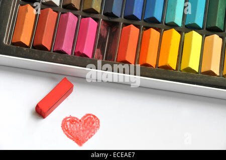 Red heart shape drawn with red chalk on black background with red small ...
