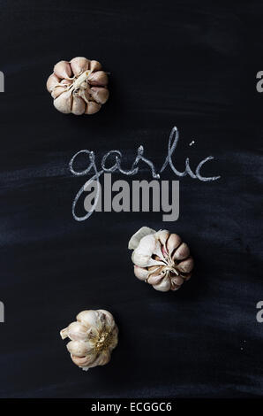 Cloves of garlic over black chalkboard with handwritten word "garlic ...