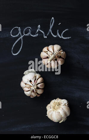 Cloves of garlic over black chalkboard with handwritten word "garlic ...
