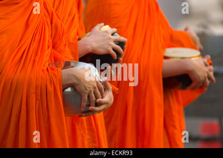 Line of monks holding traditional begging bowls during the morning alms ...
