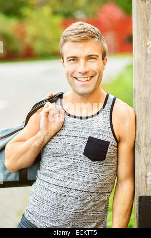 Smiling young man leaning on railing in the city holding tablet Stock ...