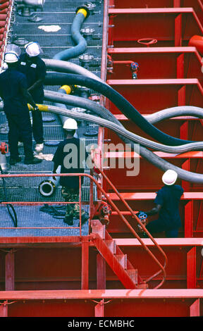 Workers secure holds, hatches and equipment on the orange deck of an ...