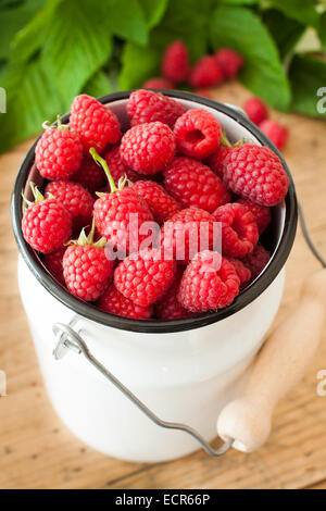 Fresh ripe raspberries with green mint leaves on black plate against ...