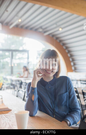 Young businesswoman sitting at table in front of computer monitor and ...