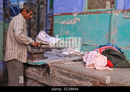 Traditional Indian street laundry man (dhobi) ironing washing on a cart ...