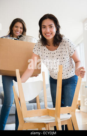 Young hispanic woman holding cardboard box at moving smiling happy ...