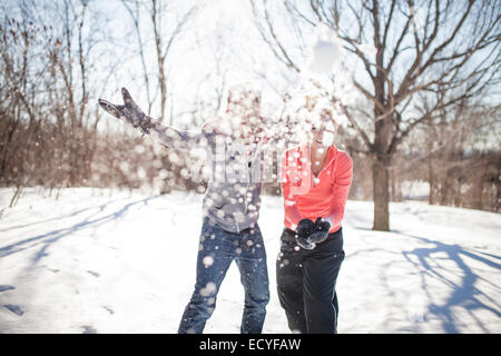 Winter activities. Couple throwing snow up in winter forest. People ...