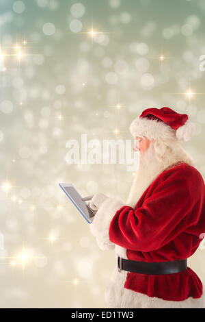 Composite image of santa uses a tablet pc and smiles into the camera ...
