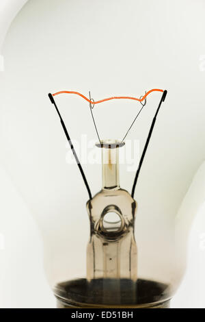 Glowing supported red hot tungsten wire filament in clear light bulb ...