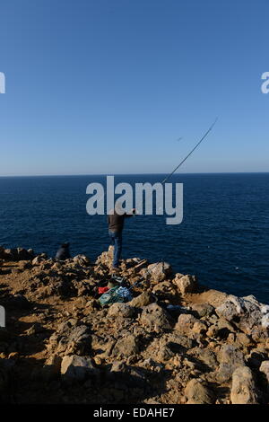 A fisherman casts his line from the rocks on the Lligwy to Dulas ...