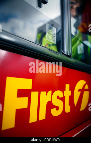 A First Group bus driver in a high visibility vest with two First Group ...
