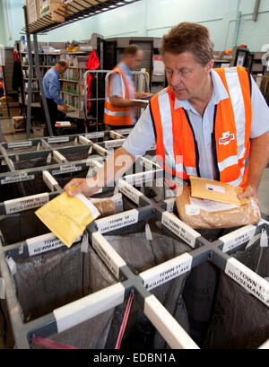 A postal worker sorts letters at a Royal Mail delivery office, Royston ...