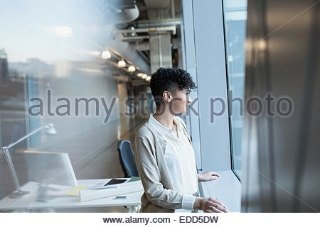 Businesswoman looking out office window Stock Photo - Alamy