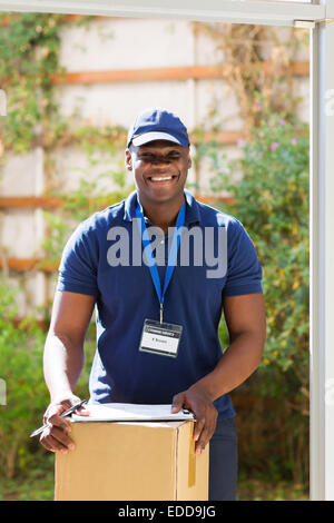handsome young delivery man standing holding a cardboard and looking at ...