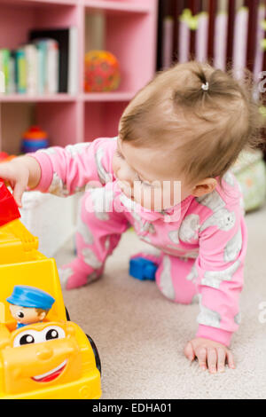 Adorable caucasian girl playing with truck toy sitting on table at ...