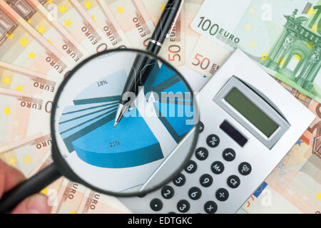 Hand with magnifying glass over a calculator, pen and money Stock Photo ...