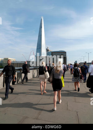 Office workers walking across bridge towards London Bridge railway ...