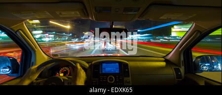 Night view out windshield of car while driving with blurred roadway and ...