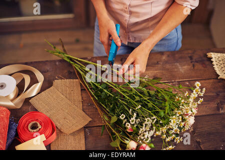 Female flower shop assistant cutting taking care of plants and cutting ...