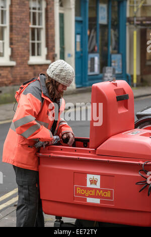 A female Royal Mail postal worker with trolley delivering post to a ...
