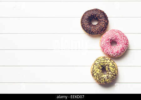 Top view of donuts in various colors and flavors on white background ...