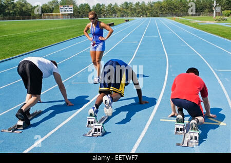 Four female athletes on starting blocks, about to start race Stock ...