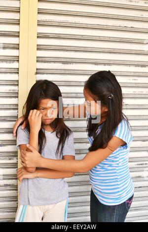 A young lady comforting a poor crying homeless child in the street ...