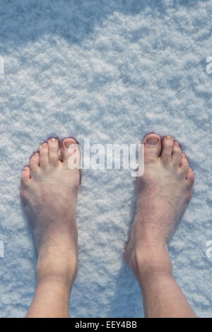 A man in winter with barefoot feet is resting on an iron bed in the ...