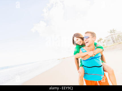 Hispanic couple doing a piggyback ride at a field with trees in the ...