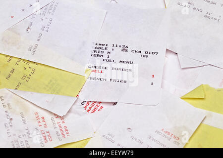 Yellow and white grease stained restaurant food order tickets in a pile ...