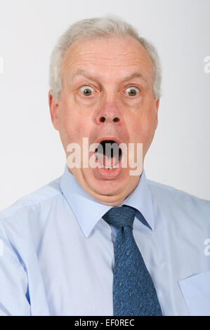 Shocked man in a blue shirt with hands on cheeks and mouth wide open ...