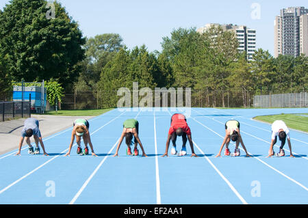 Four female athletes on starting blocks, about to start race Stock ...