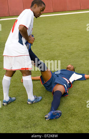 Soccer player helping opponent Stock Photo - Alamy