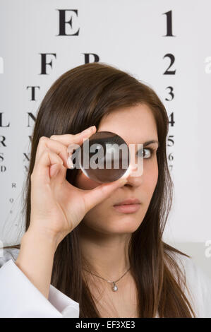 Young optometrist looking through lens of eyesight check-up equipment ...