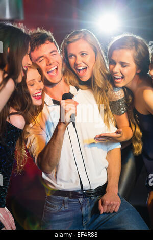 Young man singing karaoke with friends at home, selective focus Stock ...