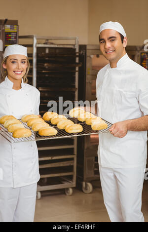 Male and female bakers working together in a bakery kitchen, discussing ...