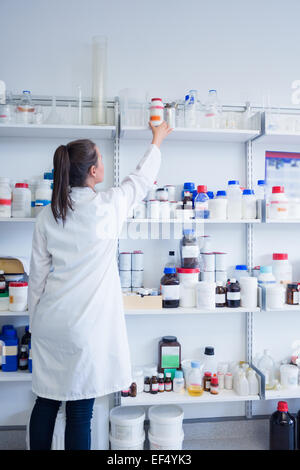 Scientist taking chemical bottle from storage compartment in ...