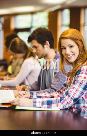 Student looking at camera while studying with classmates Stock Photo ...