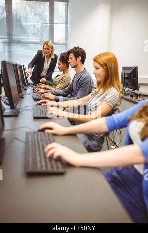 Computer teacher helping pretty female student Stock Photo - Alamy