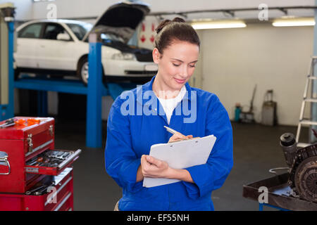 Mechanic writing on a clipboard Stock Photo - Alamy
