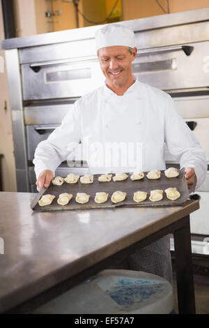 Smiling baker holding tray of raw dough Stock Photo - Alamy