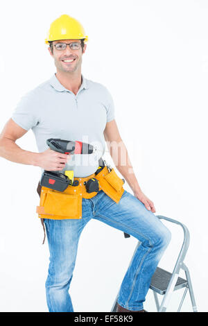 Carpenter with power drill standing by ladder at construction site ...